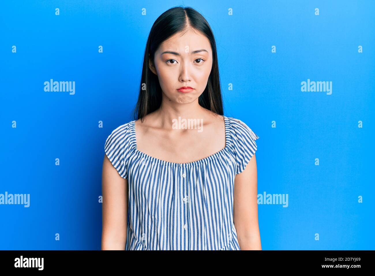 Young chinese woman wearing casual striped t-shirt depressed and worry ...