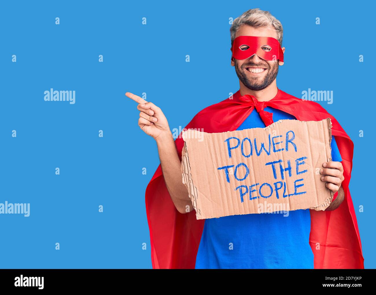 Young blond man wearing super hero custome holding power to the people ...