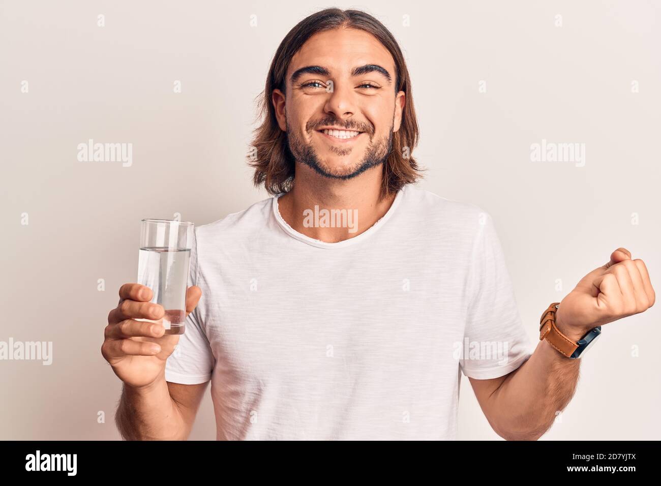 Young handsome man drinking glass of water screaming proud, celebrating ...