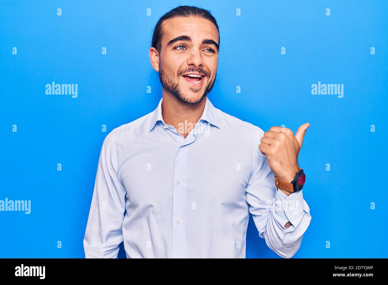 Young handsome man wearing business clothes pointing thumb up to the ...
