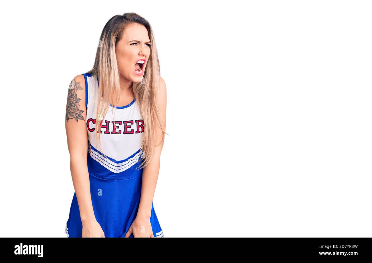 Young beautiful blonde woman wearing cheerleader uniform angry and mad ...