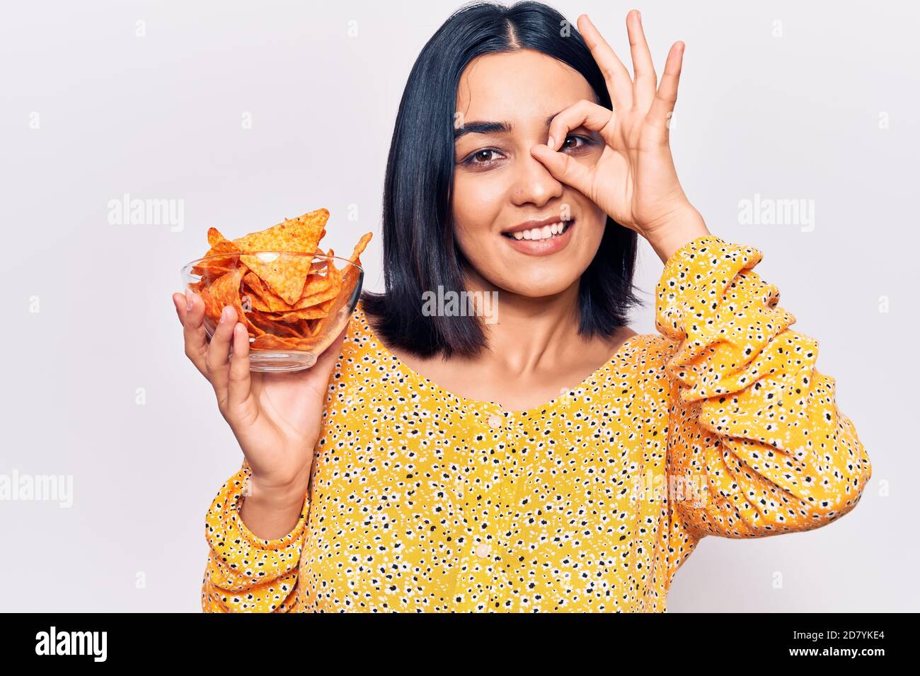 Young beautiful latin woman holding nachos potato chips smiling happy ...