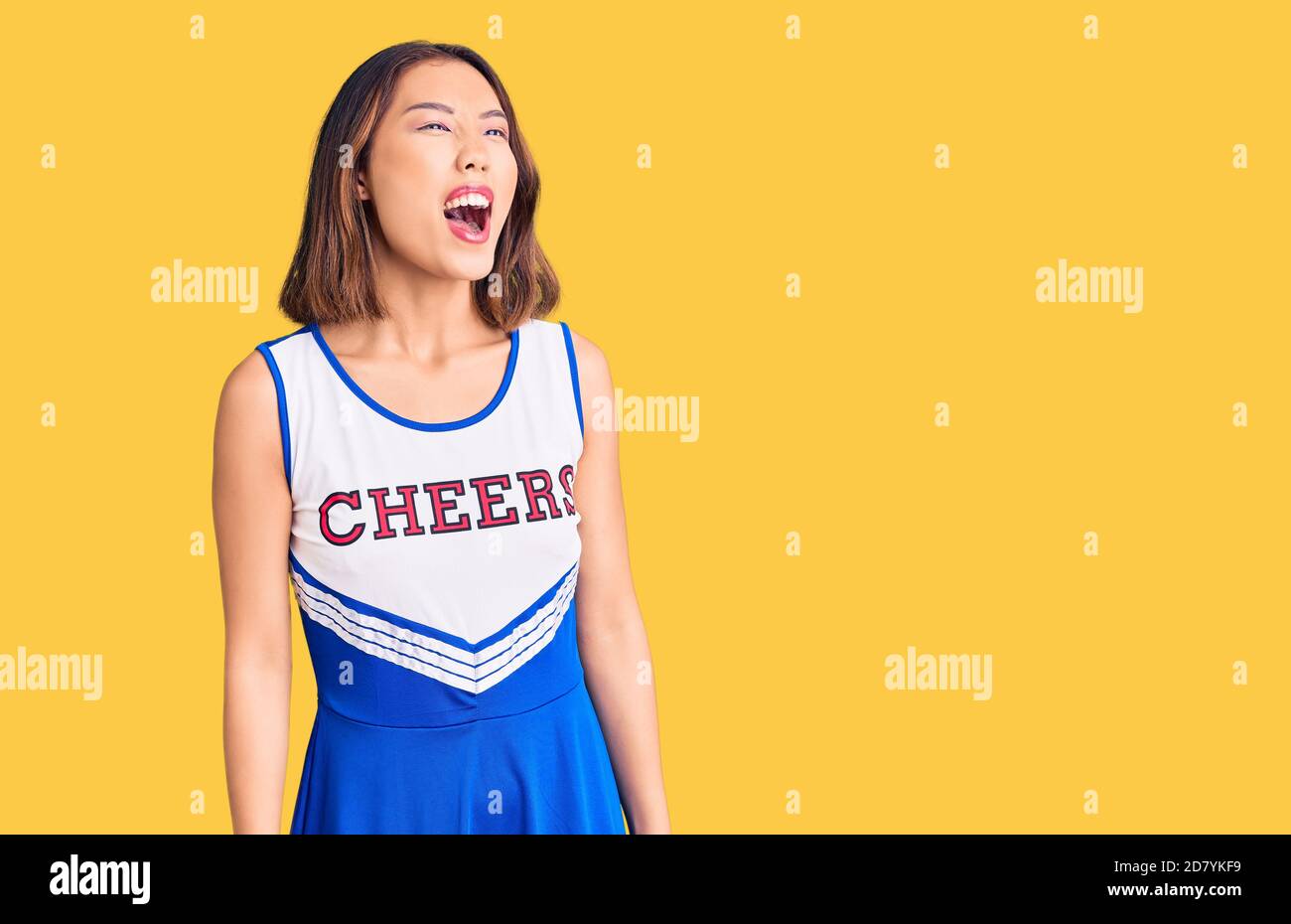 Young beautiful chinese girl wearing cheerleader uniform angry and mad ...