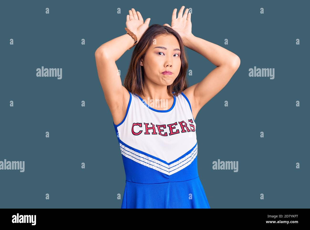 Young beautiful chinese girl wearing cheerleader uniform doing bunny ...