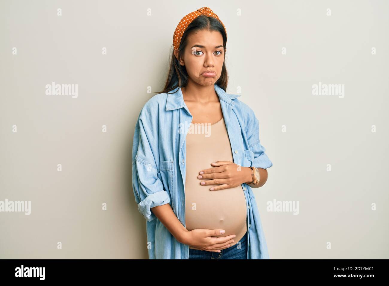 Beautiful hispanic woman expecting a baby, touching pregnant belly ...