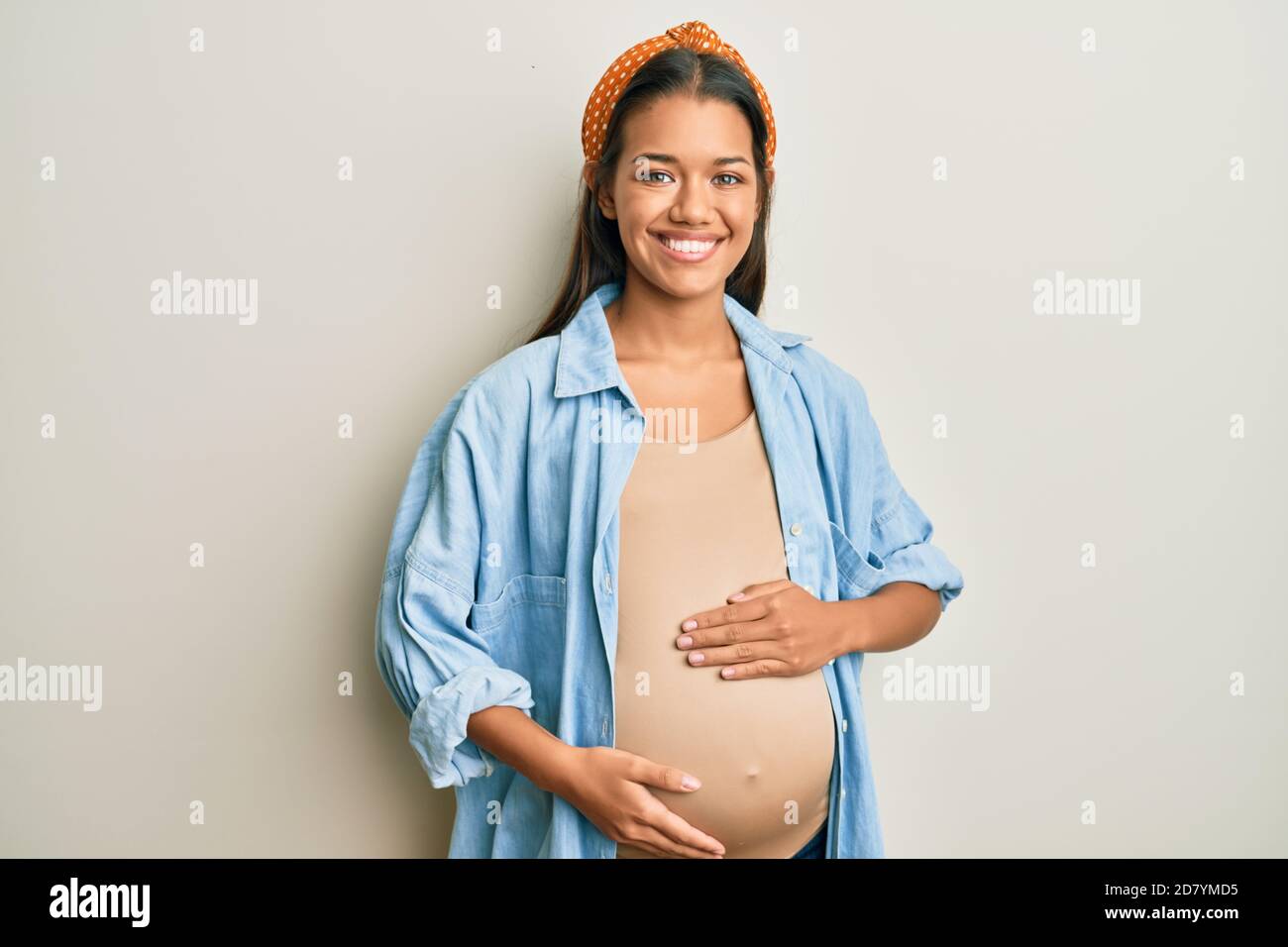 Beautiful hispanic woman expecting a baby, touching pregnant belly with ...