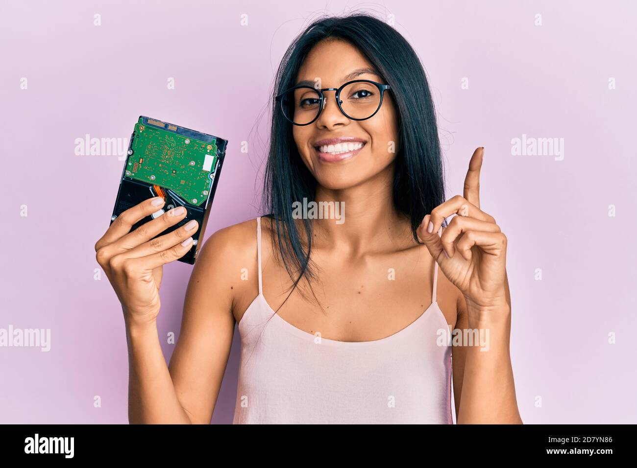 Young african american woman holding hard disk surprised with an idea ...