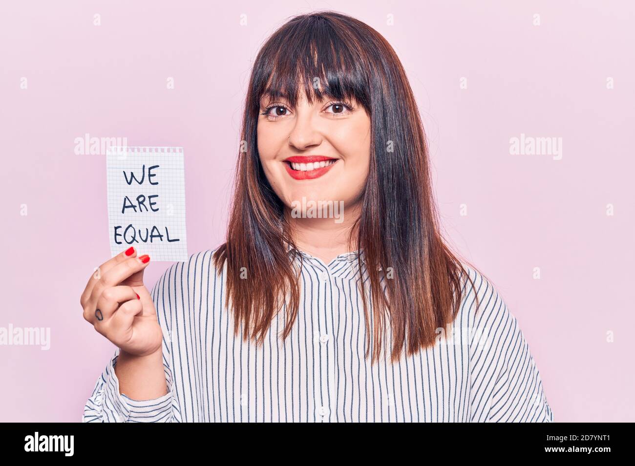 Young plus size woman holding we are equal paper looking positive and ...