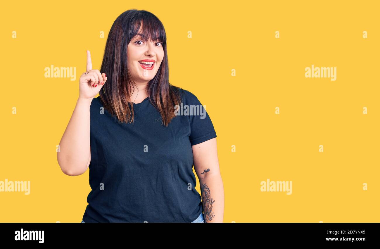 Young plus size woman wearing casual clothes pointing finger up with ...