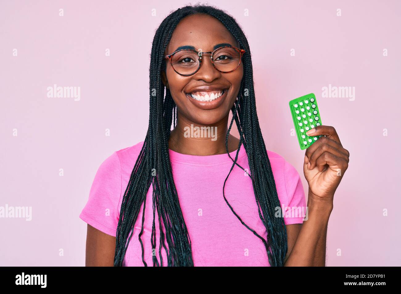 African american woman with braids holding birth control pills looking ...