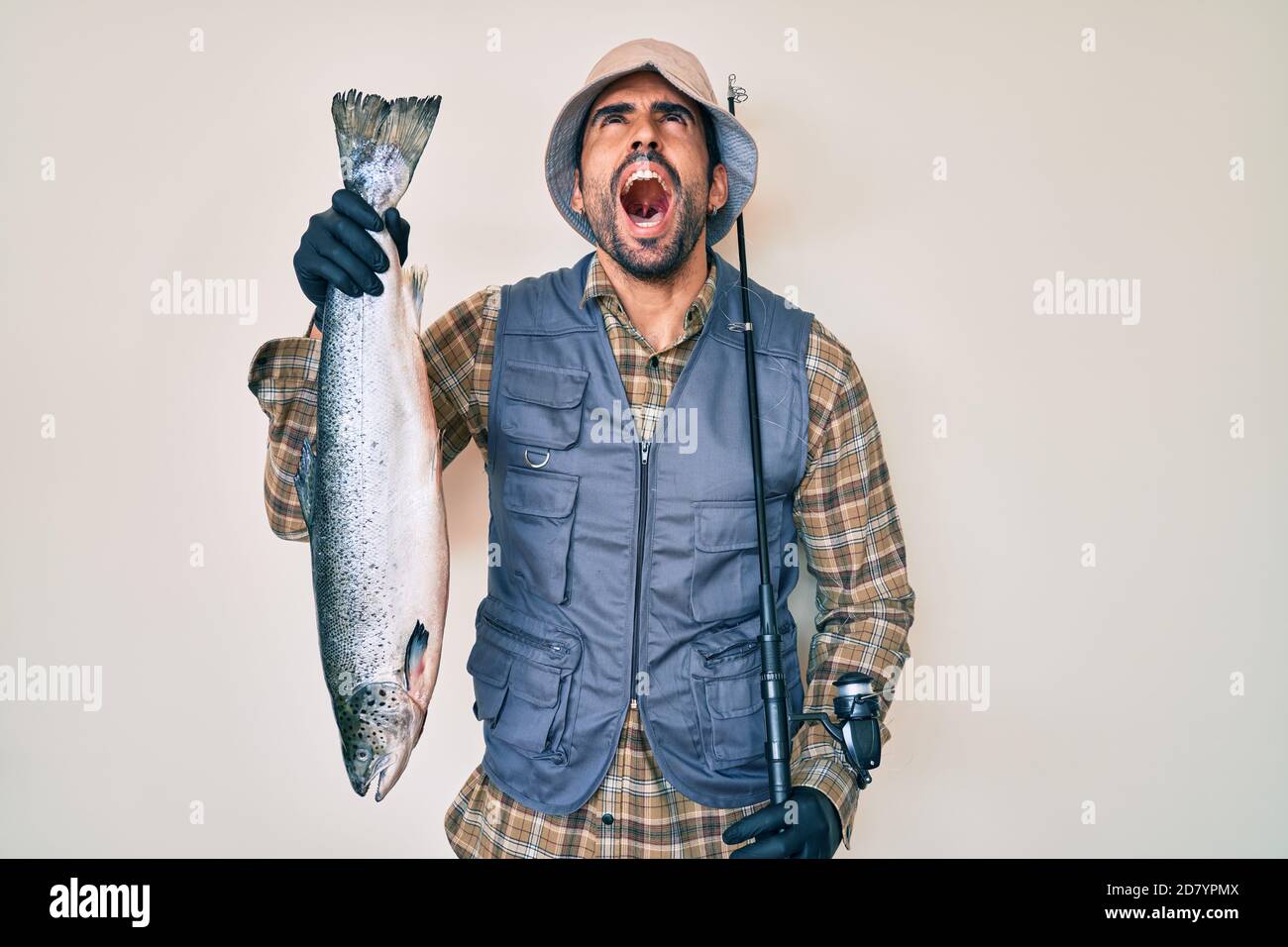 Handsome hispanic man with beard holding fishing rod and raw salmon ...