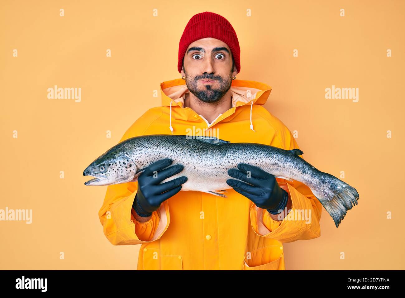 Handsome hispanic man with beard wearing fisherman equipment puffing ...