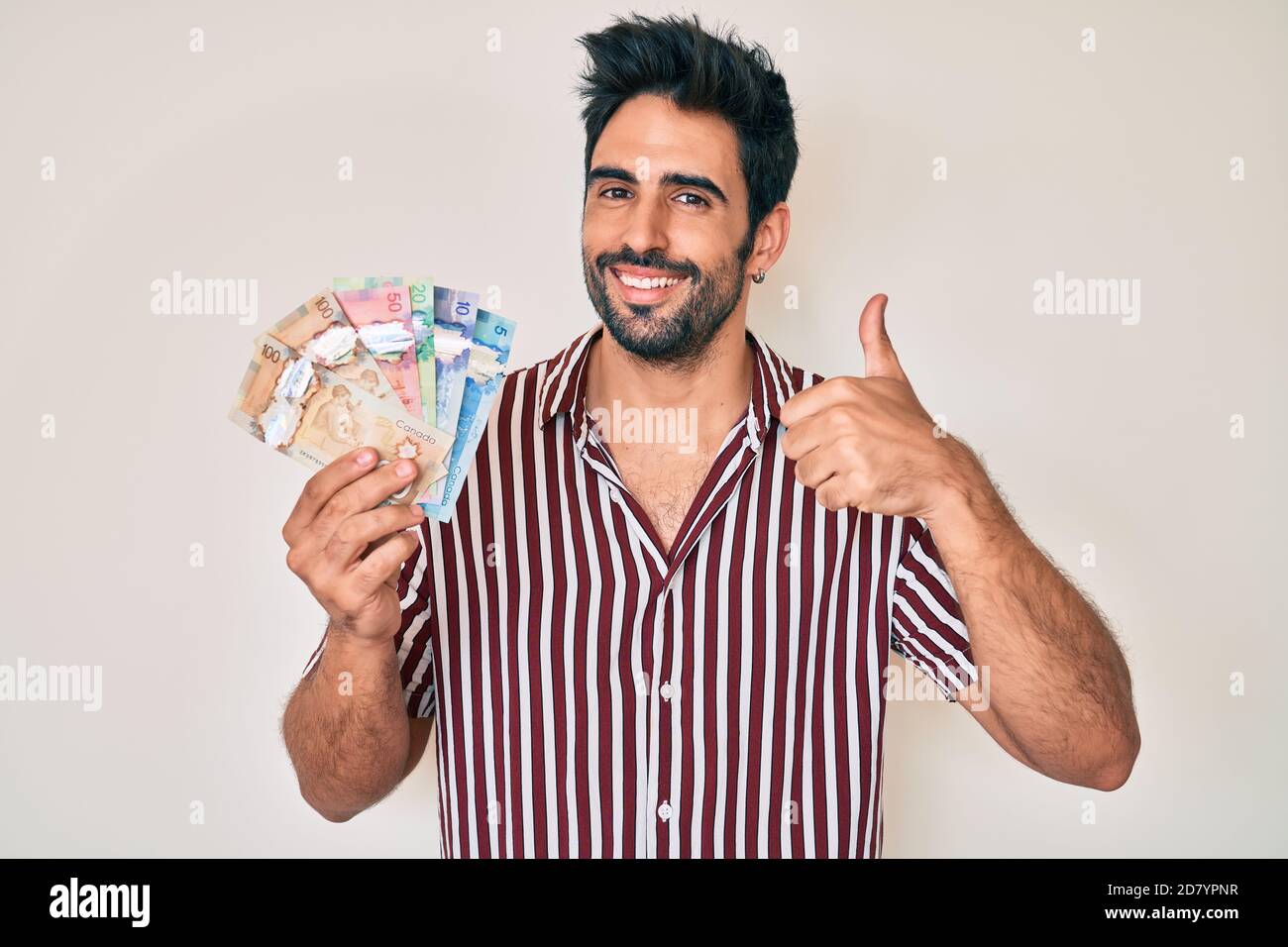 Handsome hispanic man with beard holding canadian dollars smiling happy ...