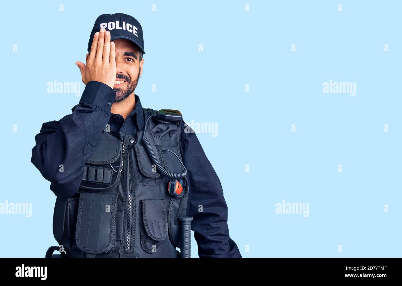 Young hispanic man wearing police uniform covering one eye with hand ...