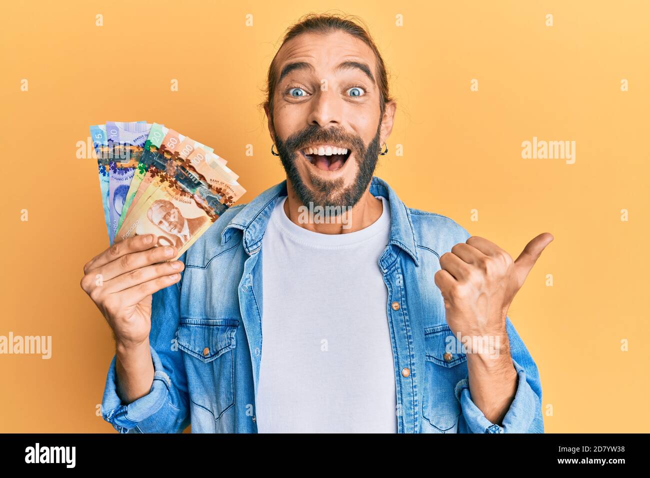 Attractive man with long hair and beard holding canadian dollars ...