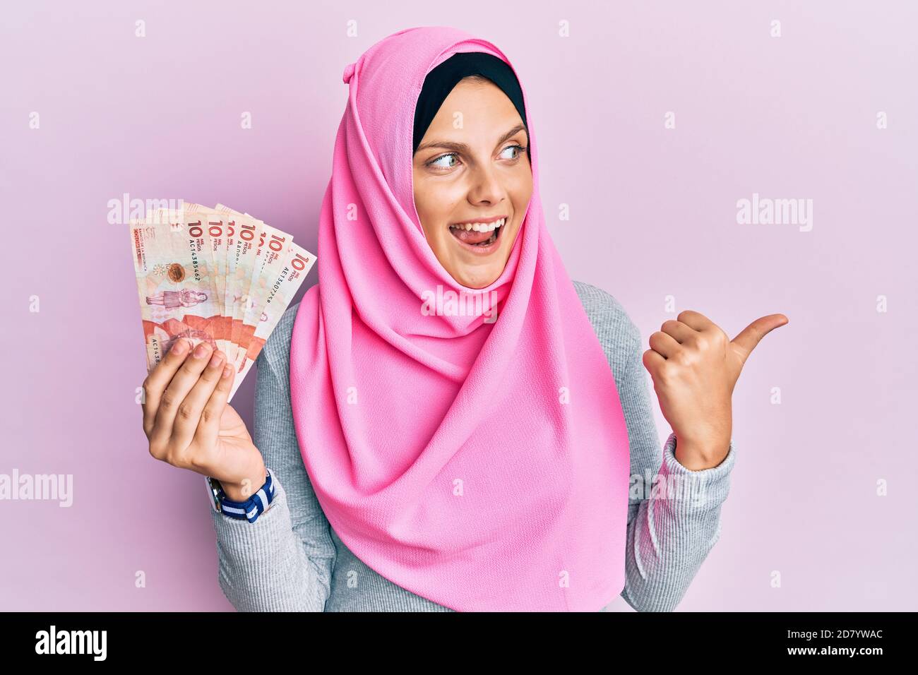 Young caucasian woman wearing islamic hijab holding colombian pesos ...