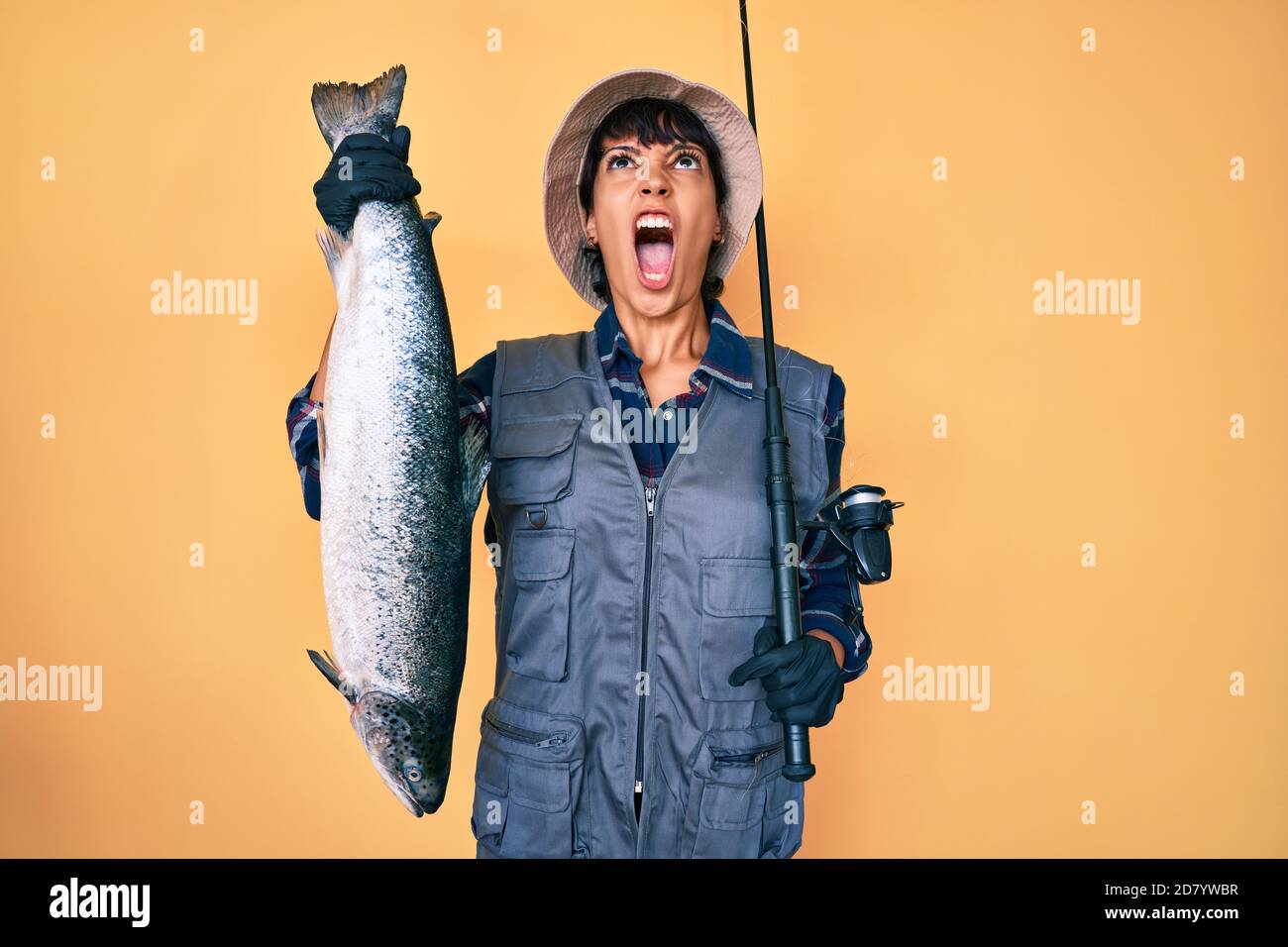 Beautiful brunettte fisher woman holding fishing rod and raw salmon ...
