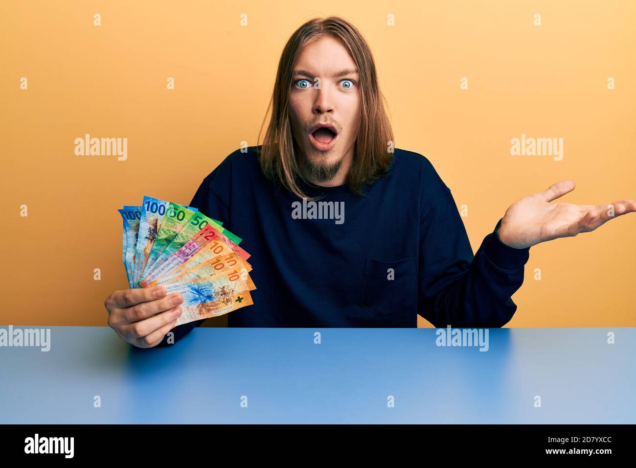Handsome caucasian man with long hair holding swiss franc banknotes ...
