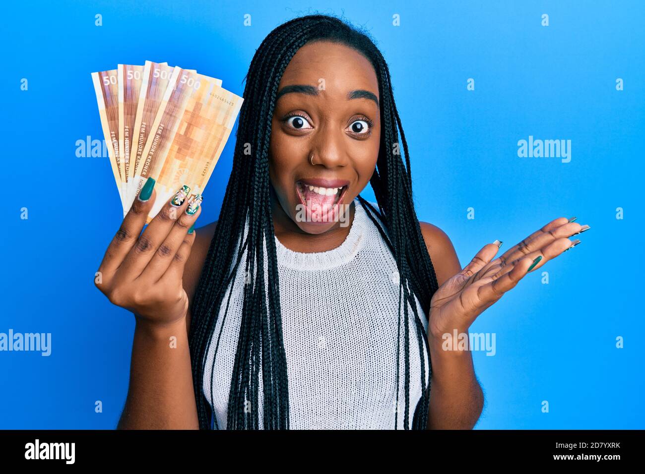 Young african american woman holding 500 norwegian krone banknotes ...