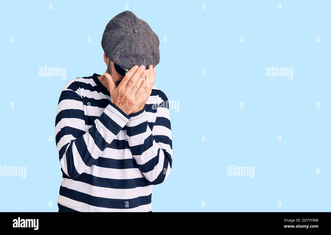 Middle age handsome man wearing burglar mask with sad expression ...