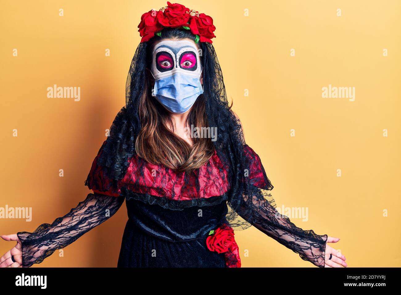 Young woman wearing day of the dead costume wearing medical mask scared ...