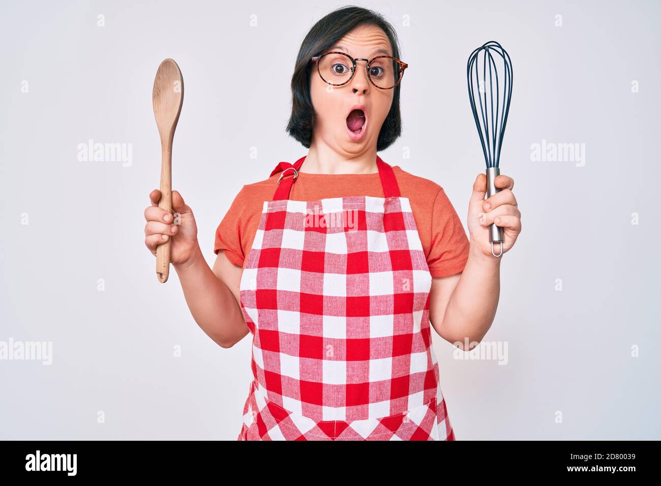 Brunette woman with down syndrome cooking using baker whisk and spoon ...