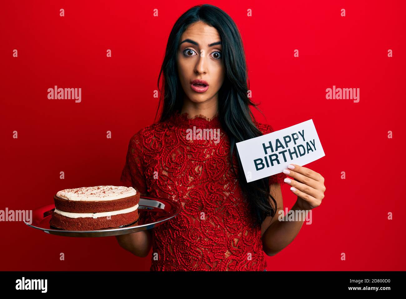 Beautiful hispanic woman celebrating birthday with cake in shock face ...