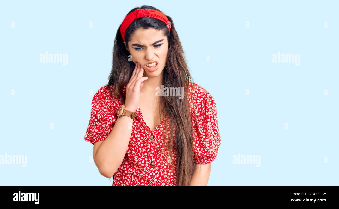 Brunette teenager girl wearing summer dress touching mouth with hand ...