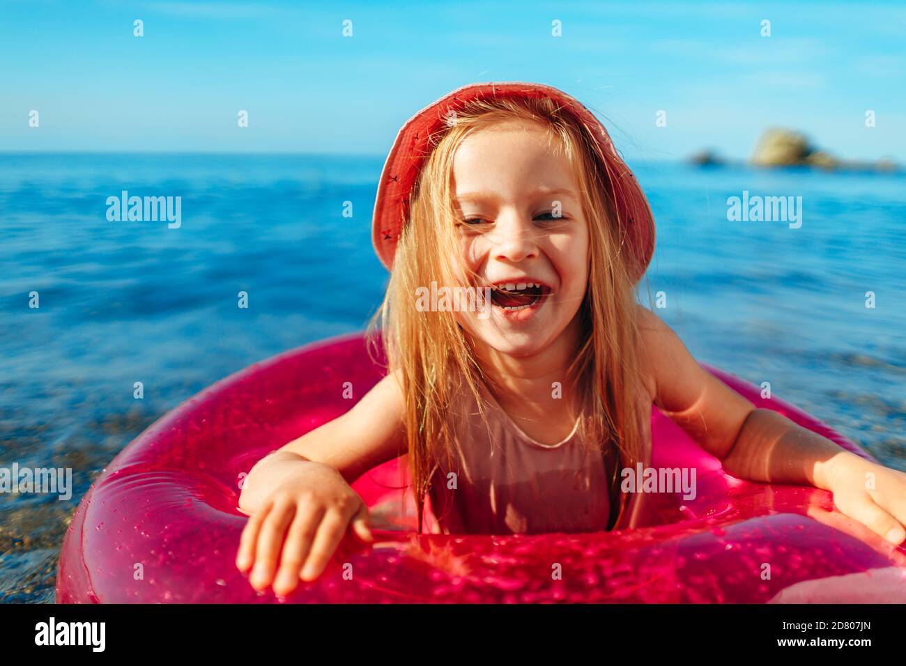 Happy little girl bathing in sea with pink circle Stock Photo - Alamy