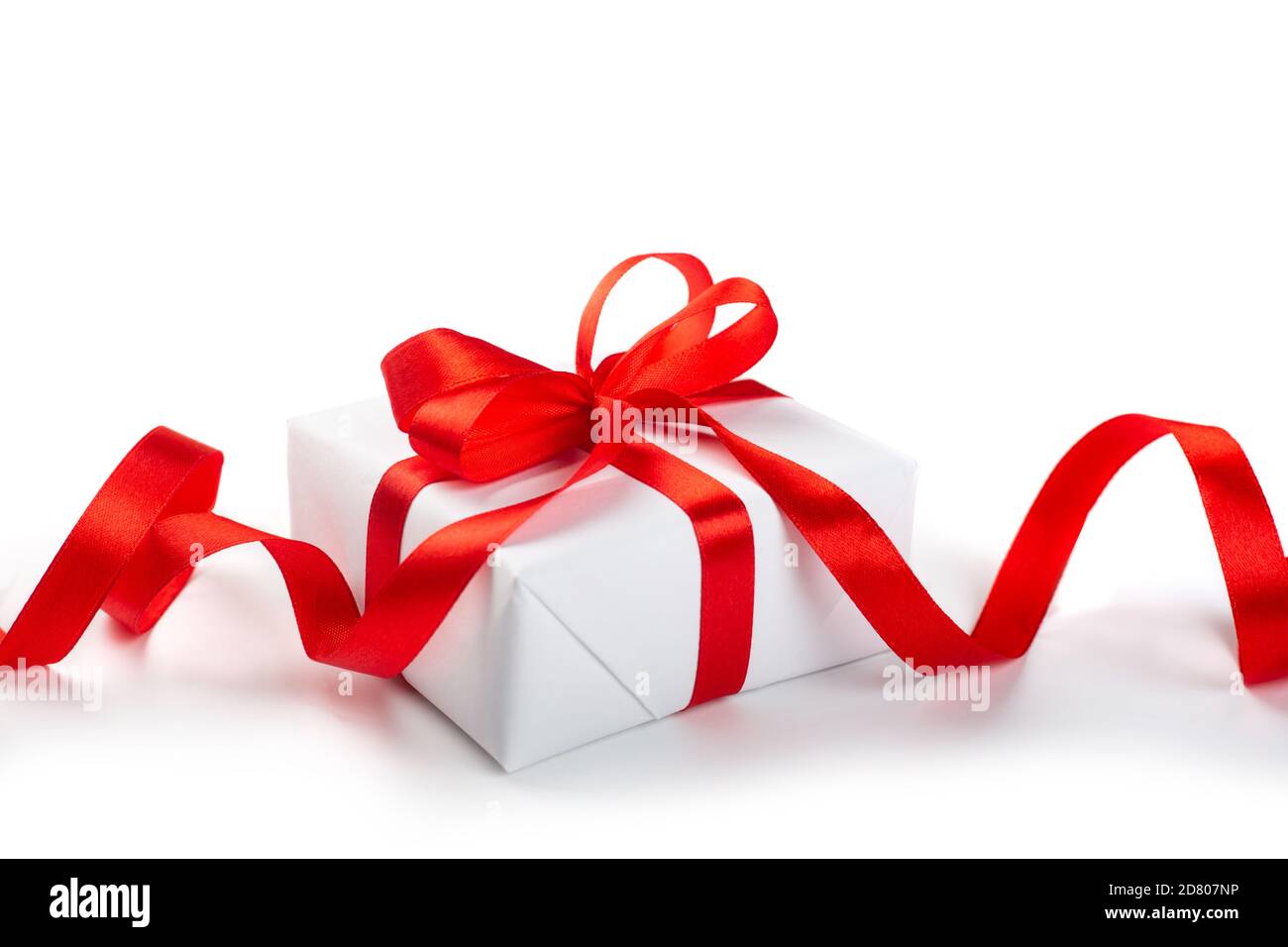 White holiday present gift box with red satin bow and curly ribbon ...