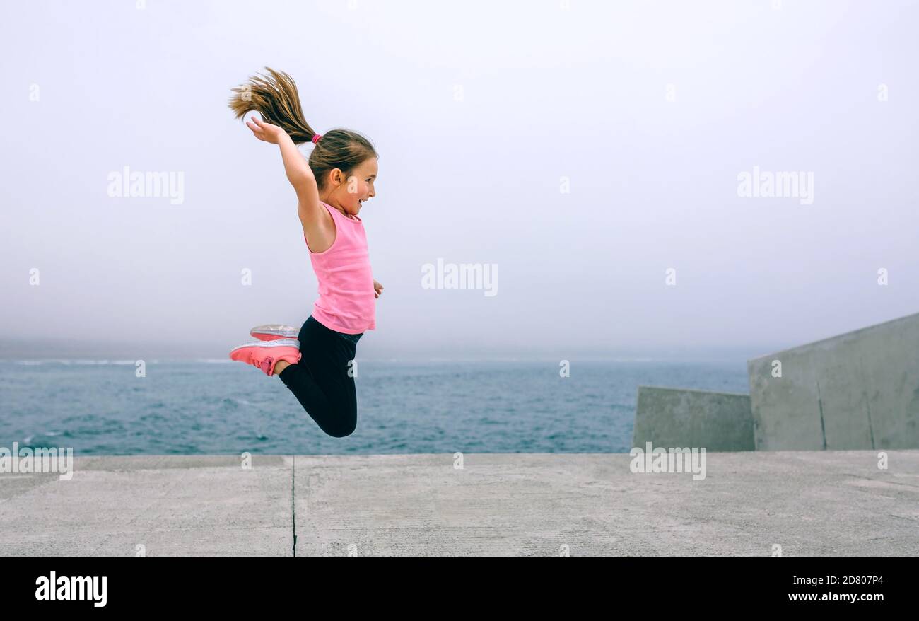 Little girl jumping by sea pier Stock Photo - Alamy