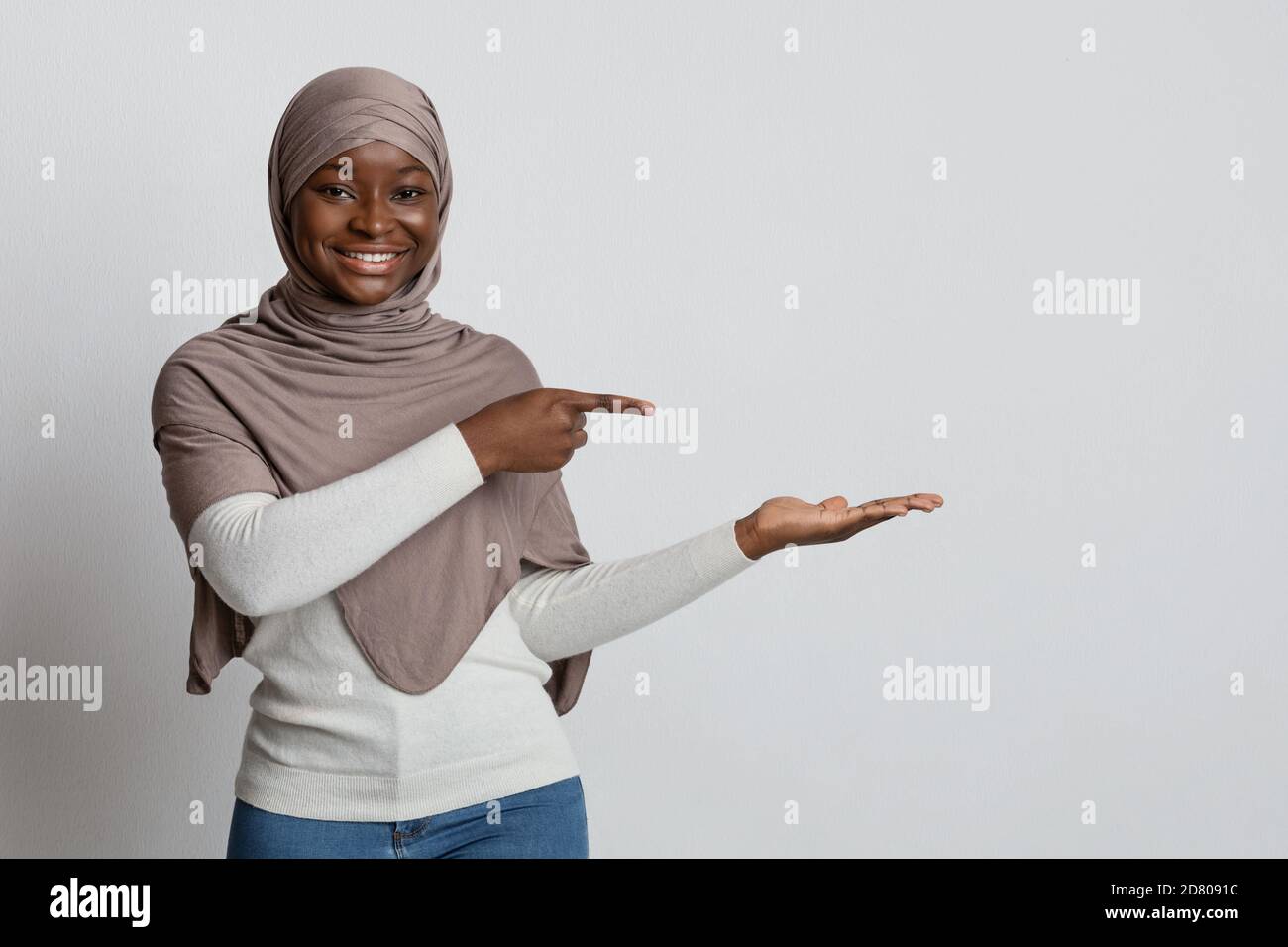 Smiling Black Muslim Lady In Hijab Pointing Finger At Her Open Palm ...