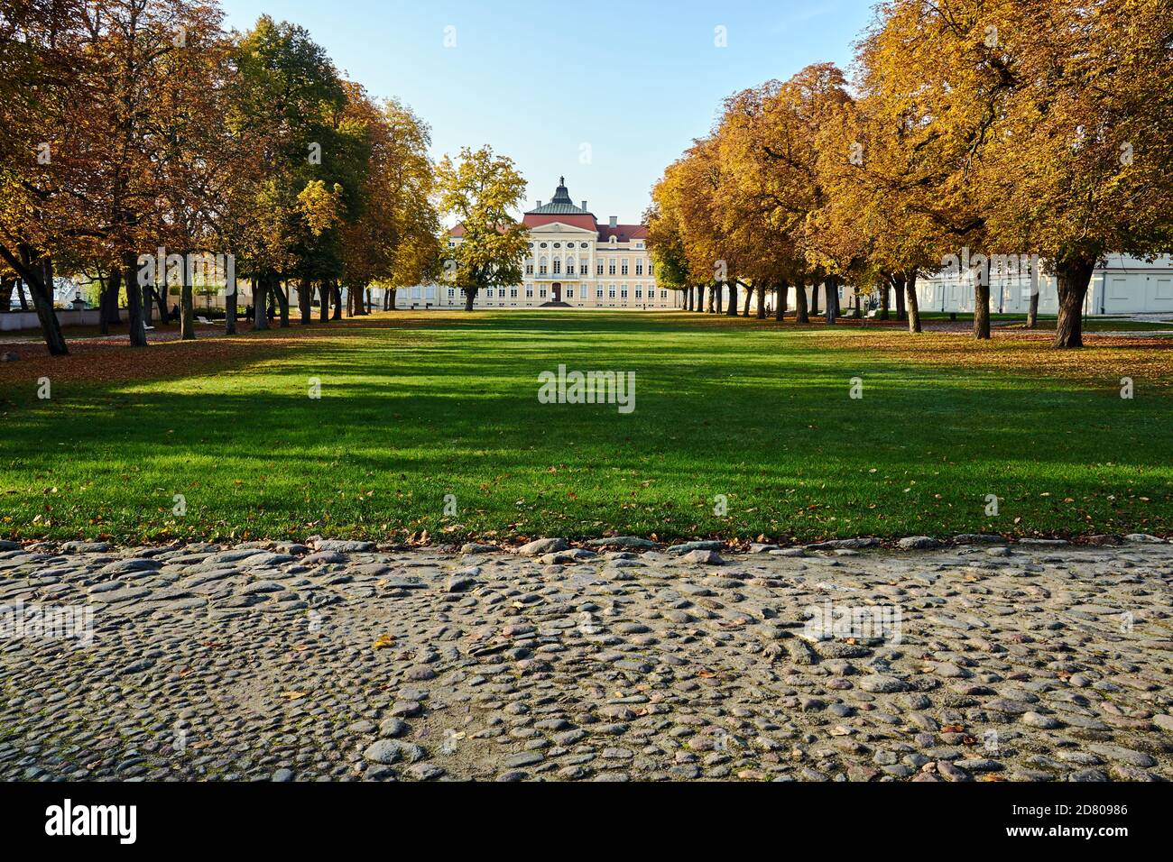 paved road, park and façade of a baroque palace during autumn in ...