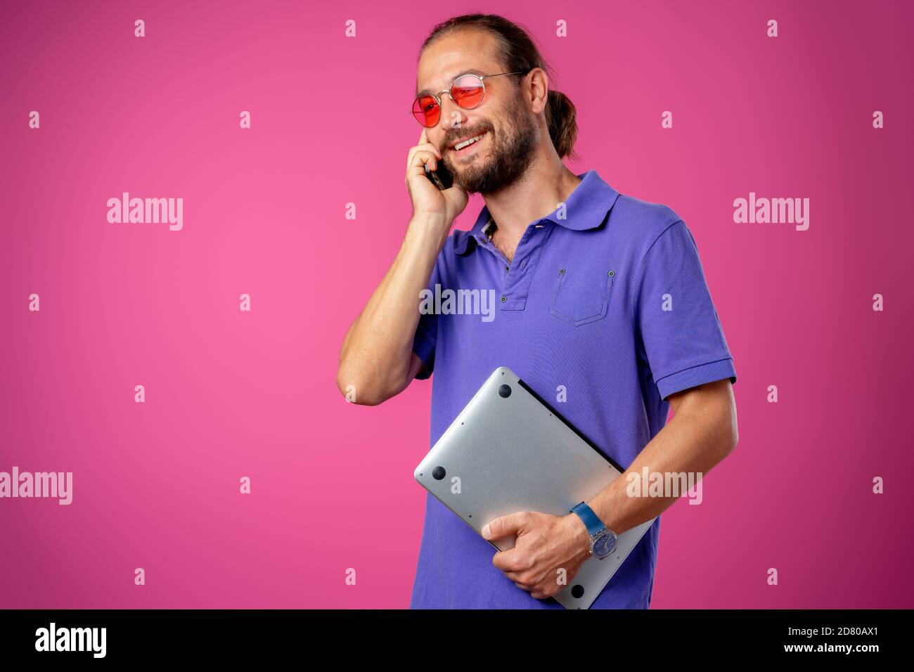 Man in glasses standing with laptop against pink background Stock Photo ...