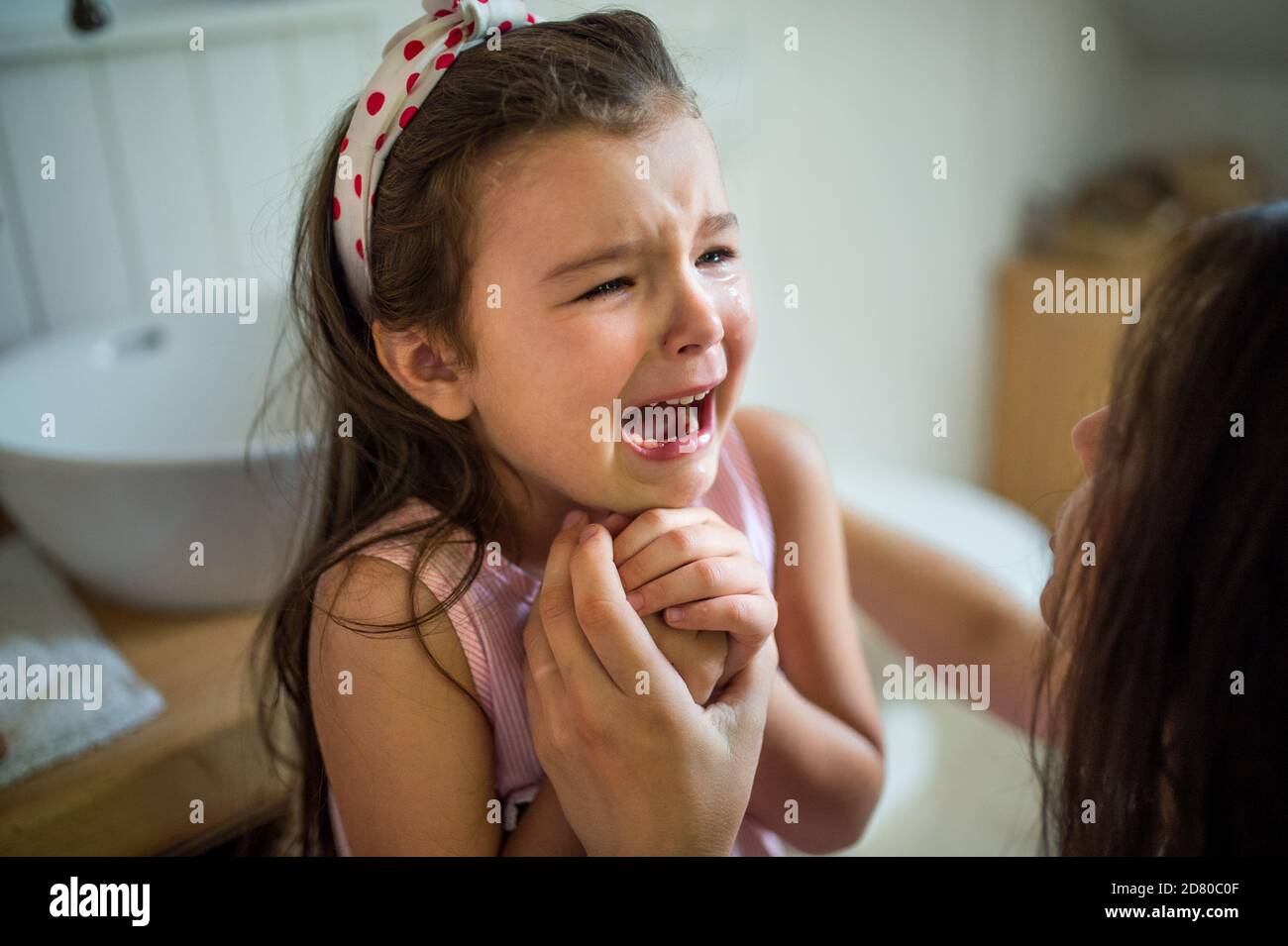 Crying small girl with unrecognizable mother indoors, loosing baby ...