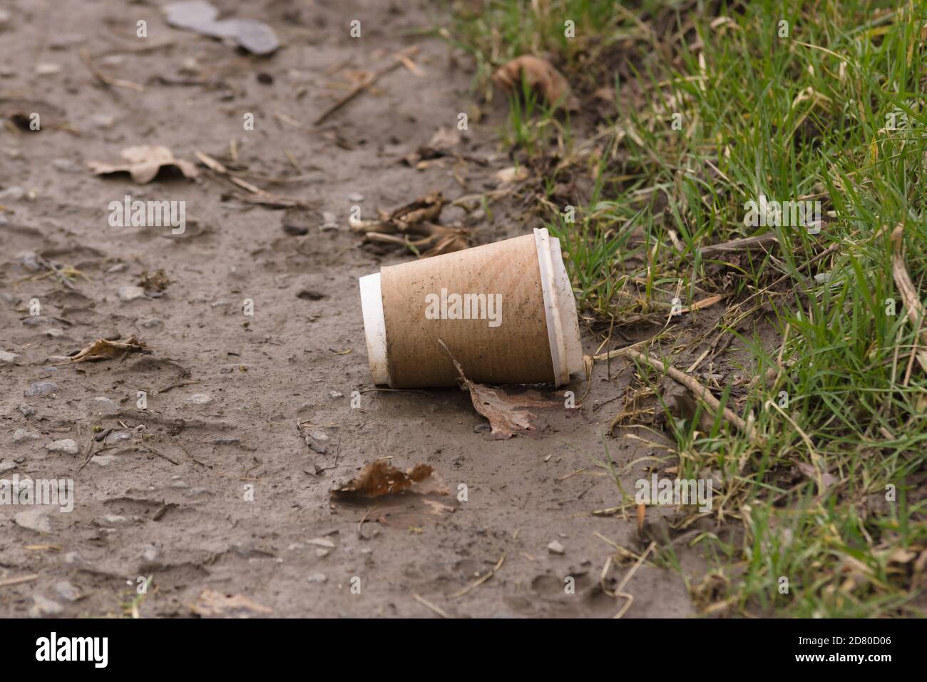 Discarded coffee cup with a plastic lid dumped on a rural lane in the ...