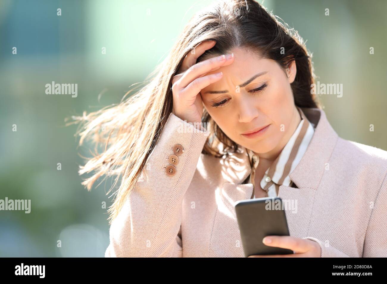 Sad entrepreneur complaining checking smart phone content in the street ...