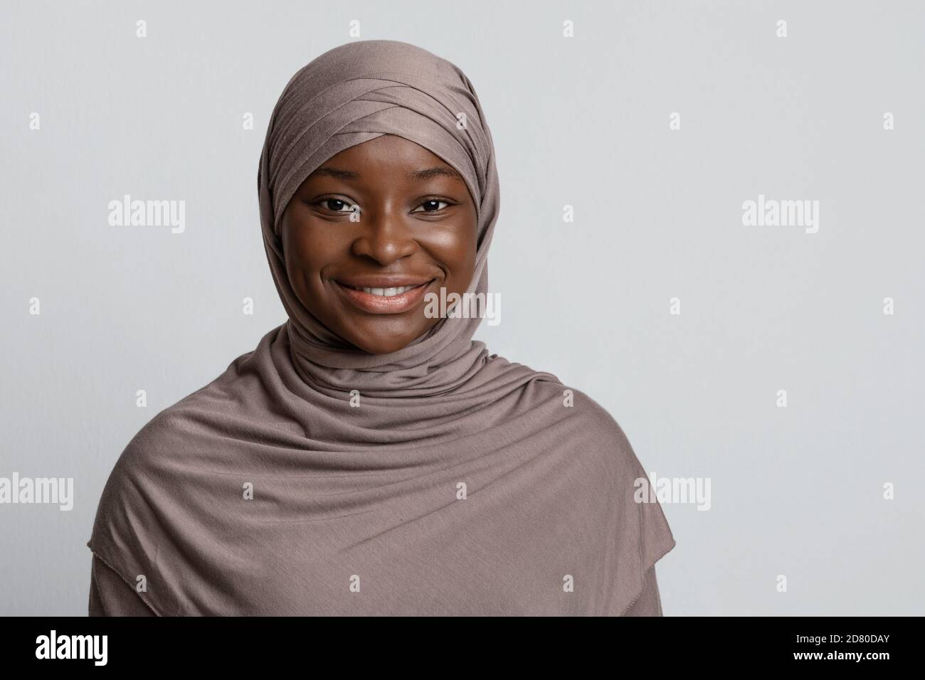 Portrait of beautiful african muslim woman in hijab over light studio ...