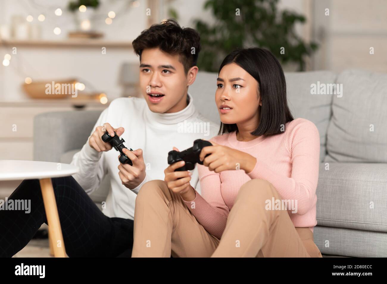 Chinese Millennial Couple Playing Computer Game Sitting At Home Stock ...