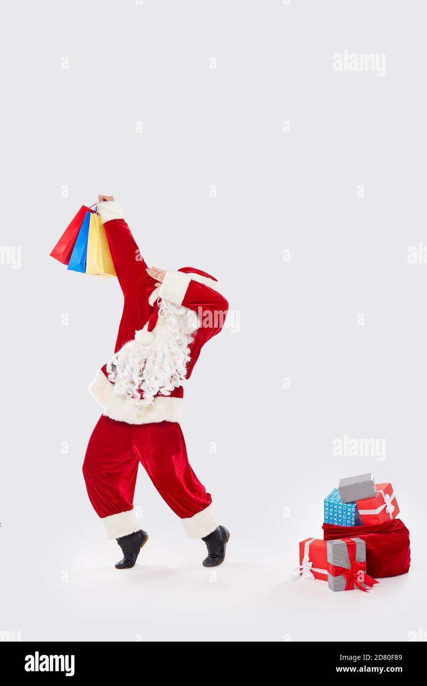 Joyful Santa claus on red costume dancing dab step with shopping bags ...