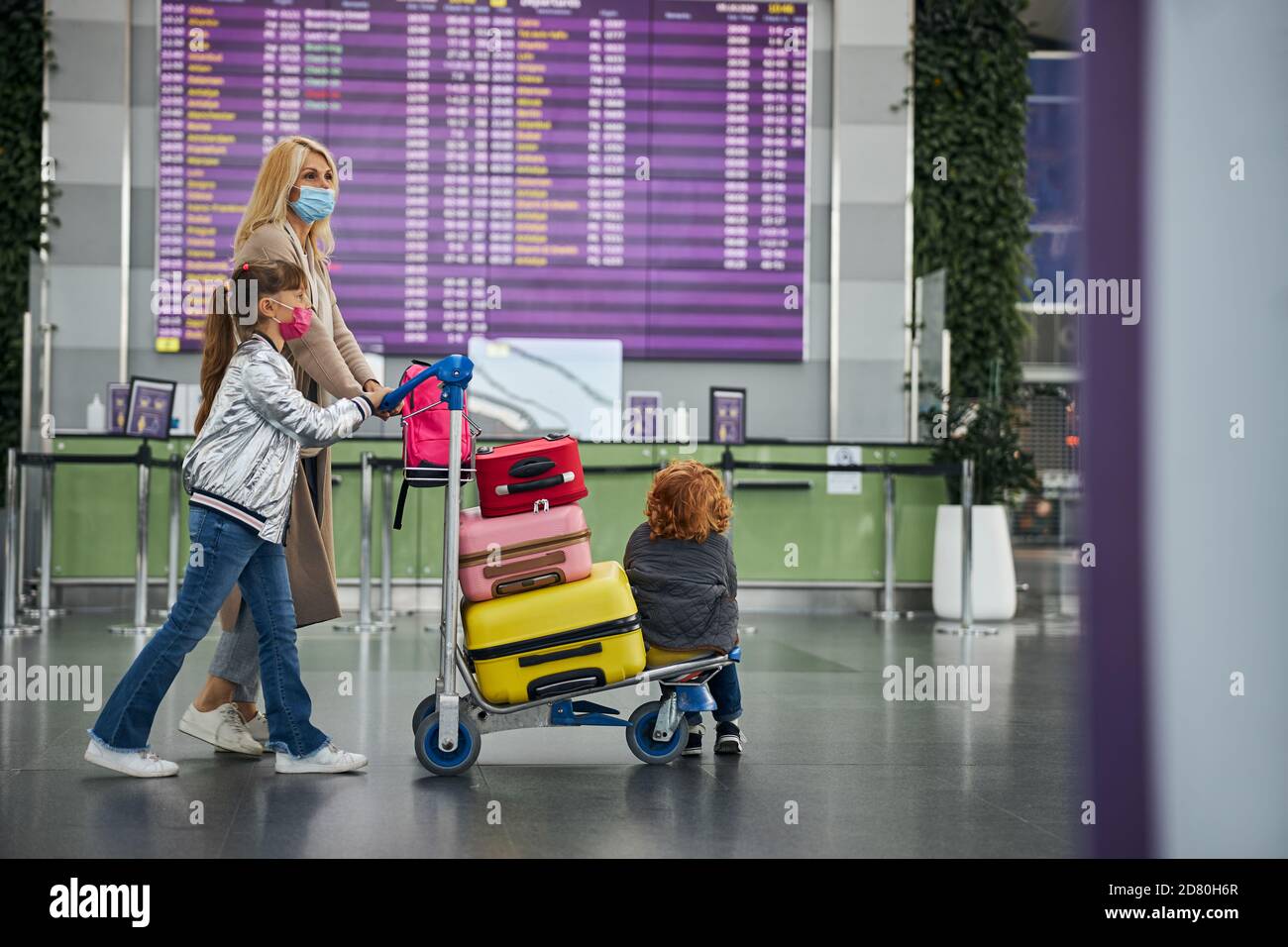 Woman and a girl pushing a trolley with a kid Stock Photo - Alamy