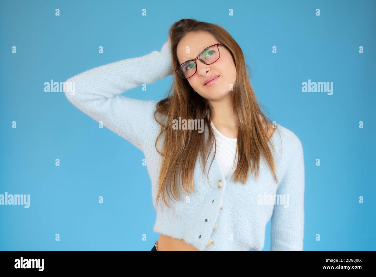 Teenager girl over blue wall making doubts gesture while lifting the ...