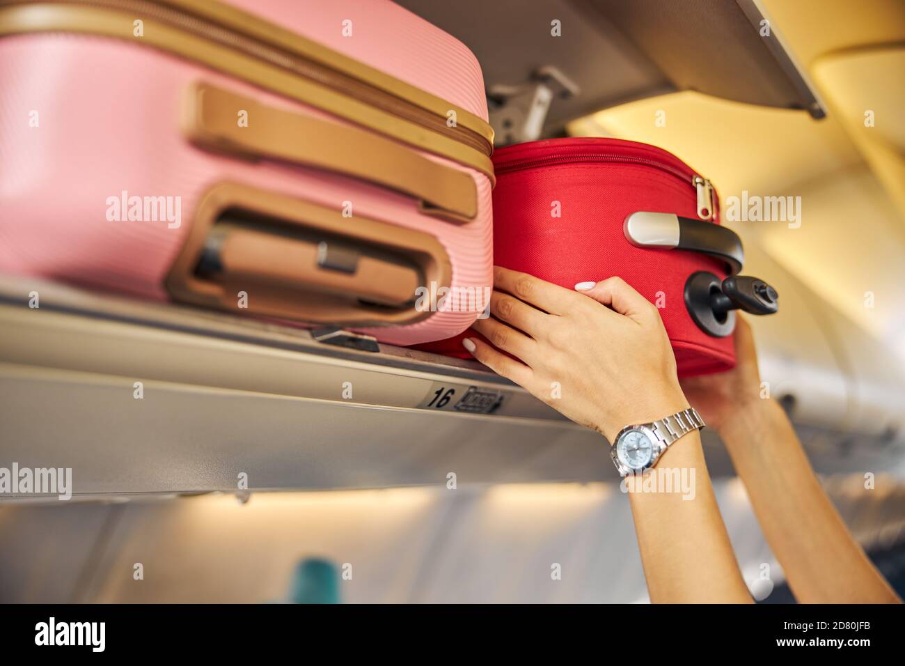 Hands laying down a carry-on baggage on an upper shelf Stock Photo - Alamy