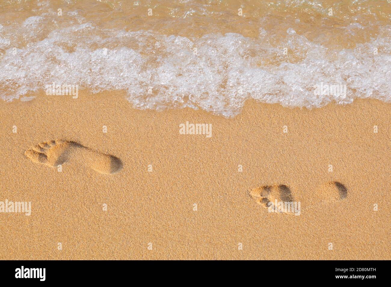 Texture background Footprints of human feet on the sand near the water ...