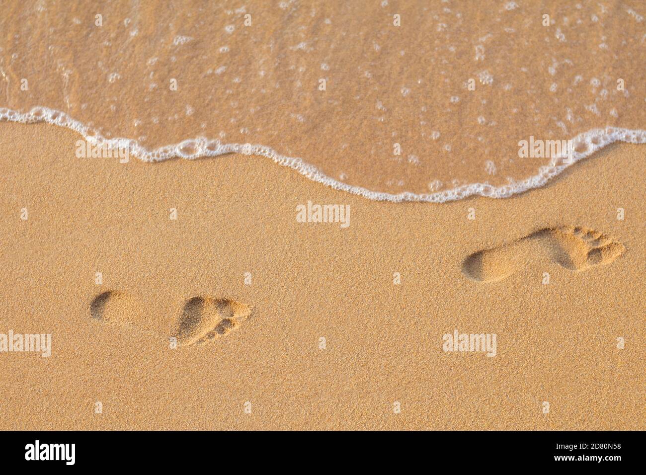 Texture background Footprints of human feet on the sand near the water ...