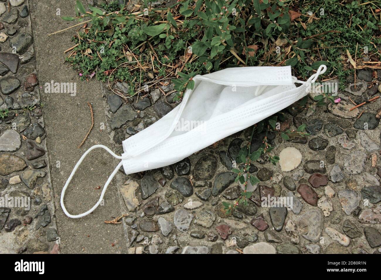 Surgical face mask thrown on the ground Stock Photo - Alamy