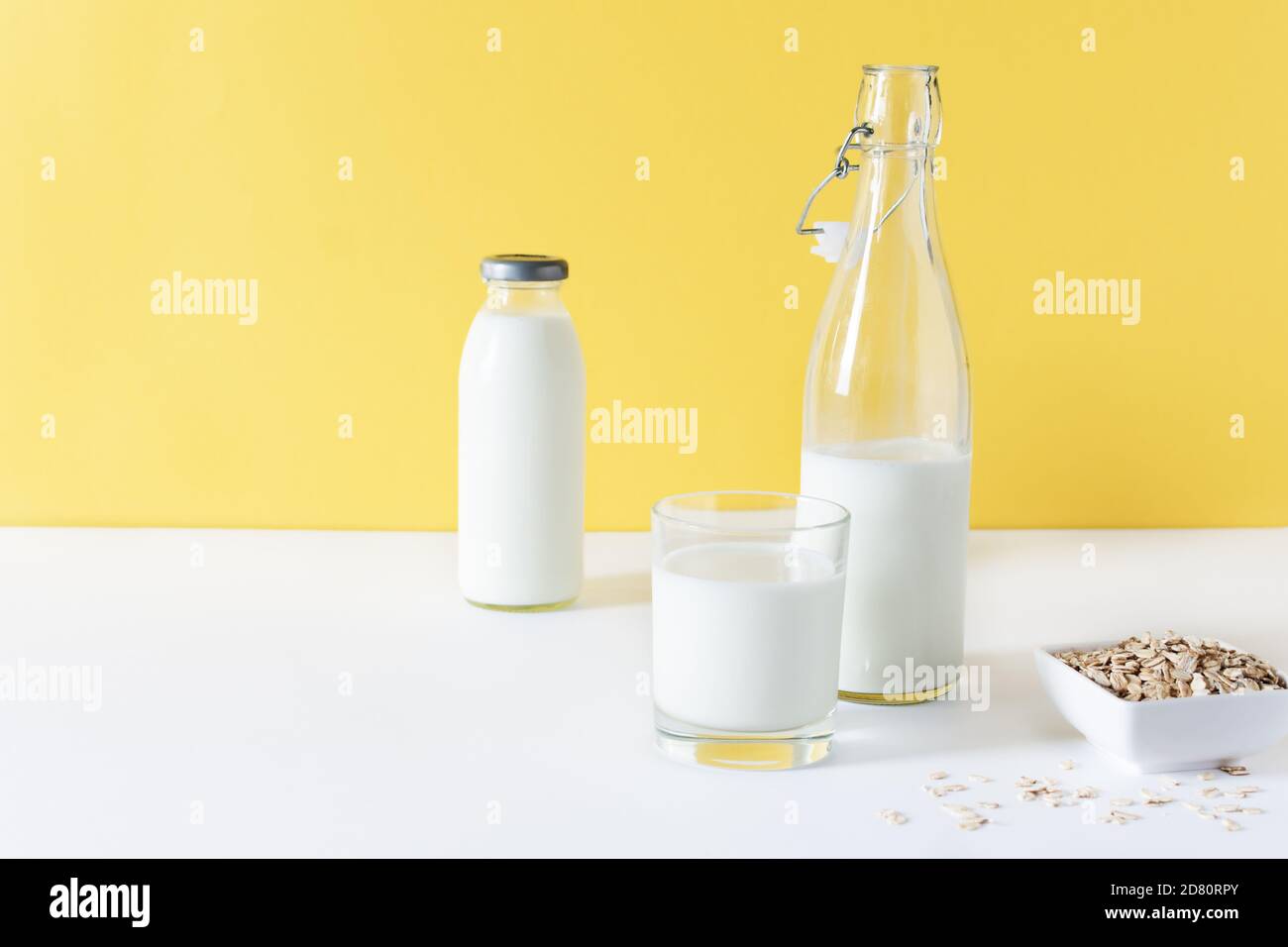 Vegan oat milk on white table over yellow wall. Homemade non dairy ...