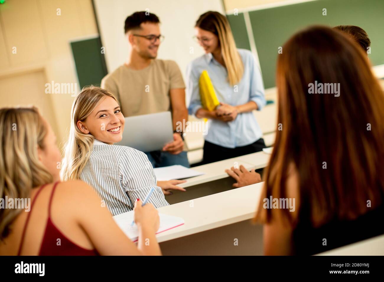 Group of university students in the classroom with young female ...