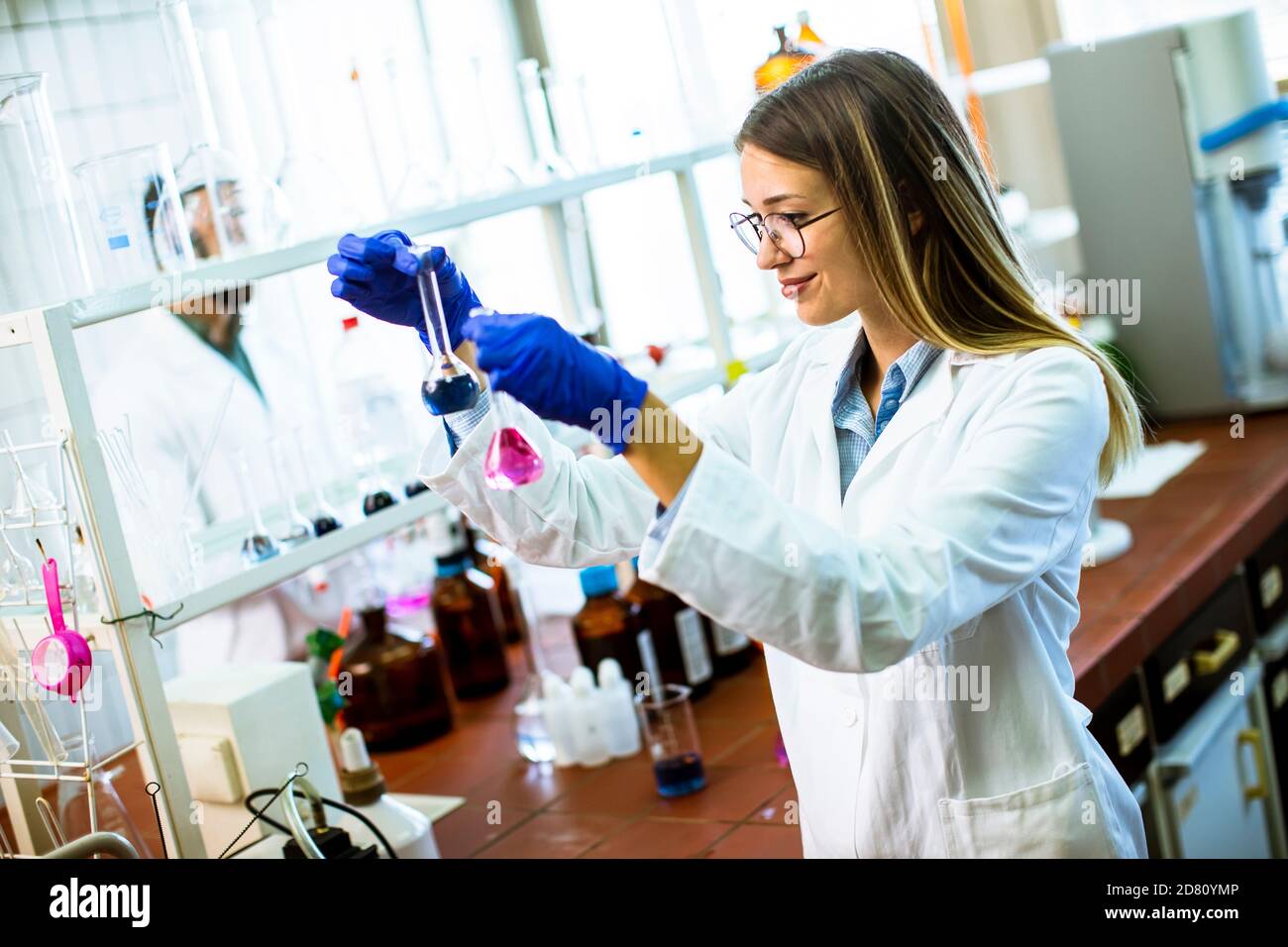 Pretty young female scientist examining liquid in biochemical lab Stock ...
