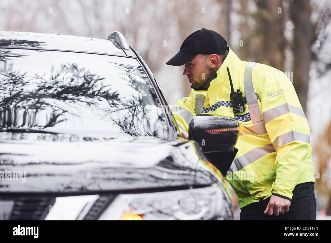 Male police officer in green uniform checking vehicle on the road Stock ...